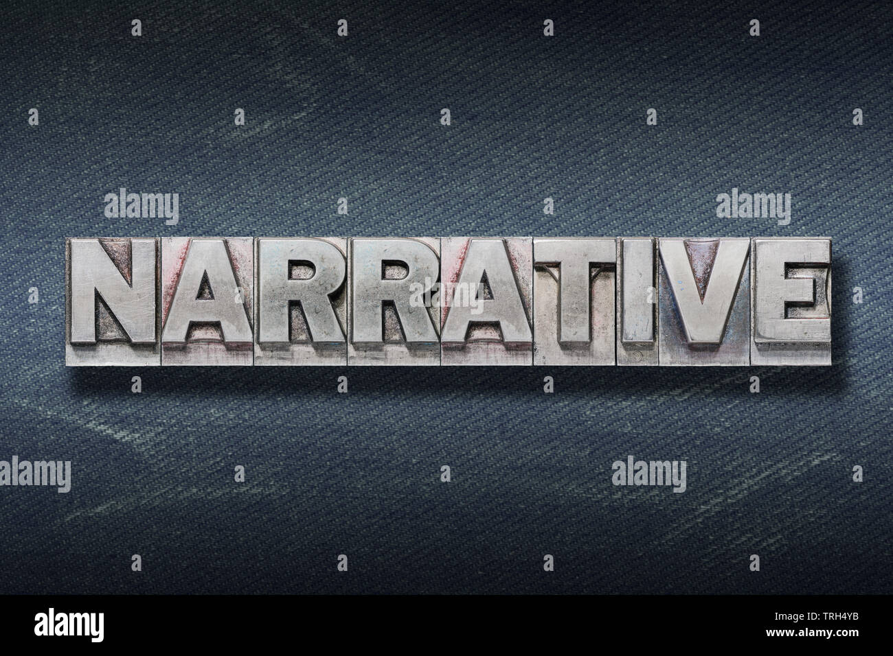 narrative word made from metallic letterpress on dark jeans background ...