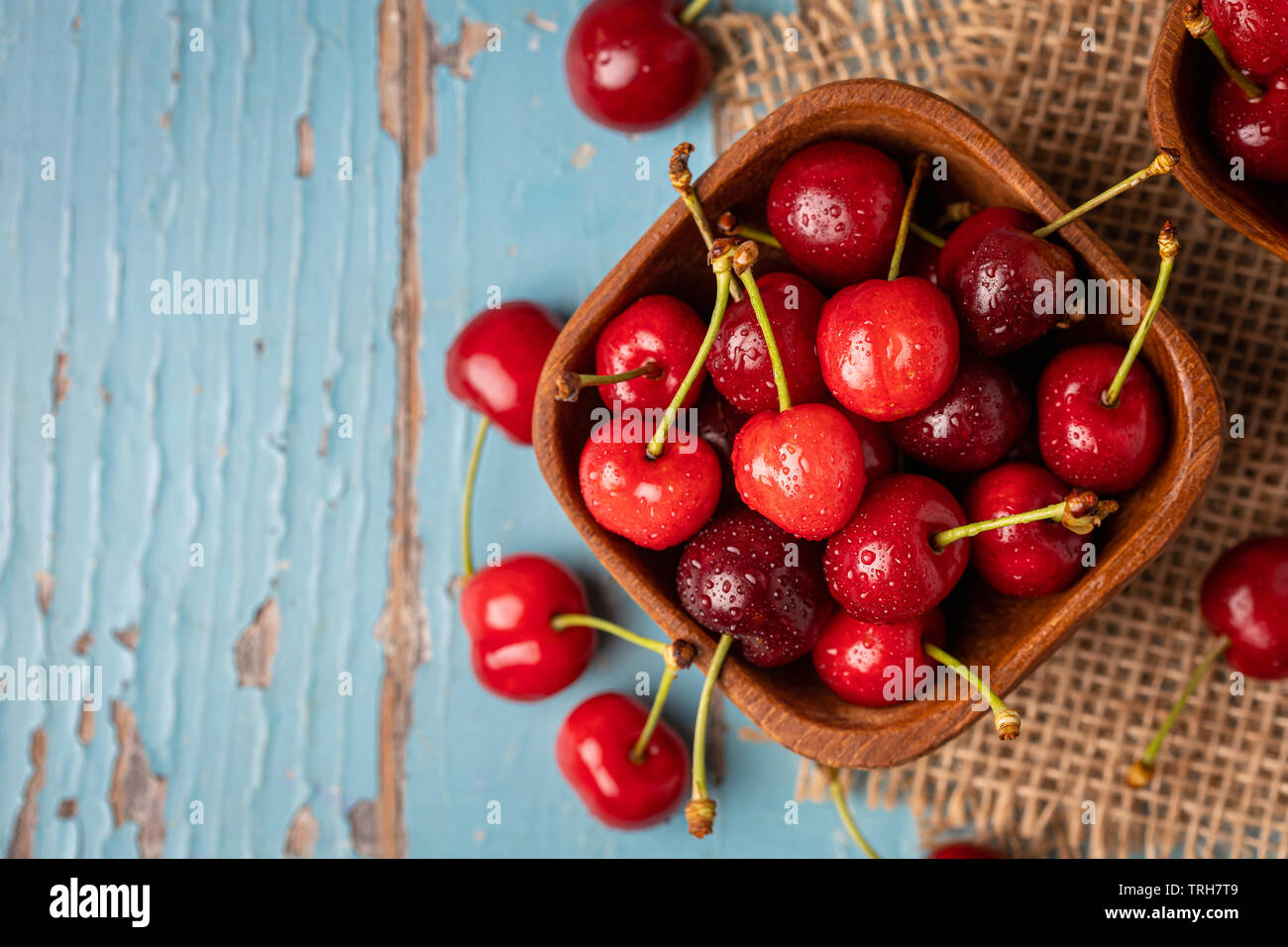 Fresh ripe cherries on blue rustic wooden background. Top view with ...