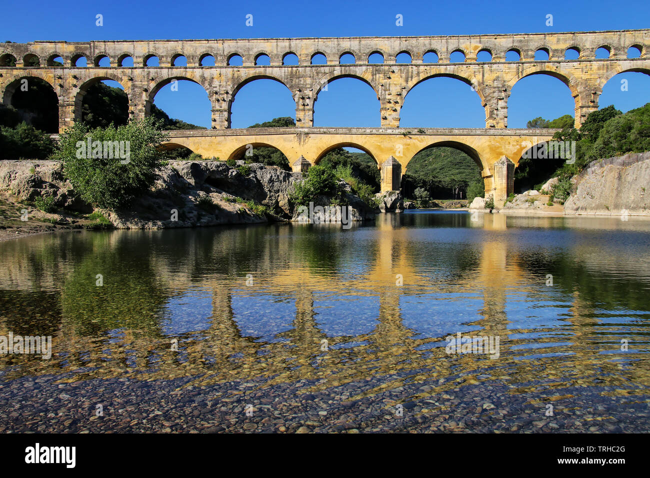 Aqueduct Pont du Gard reflected in Gardon River, southern France. It is ...