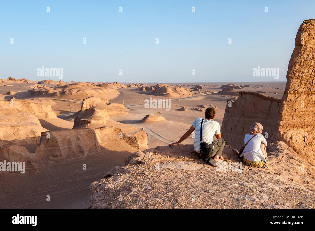 Tourists watch the sunset over yardangs, called kuluts in Iran, in the ...