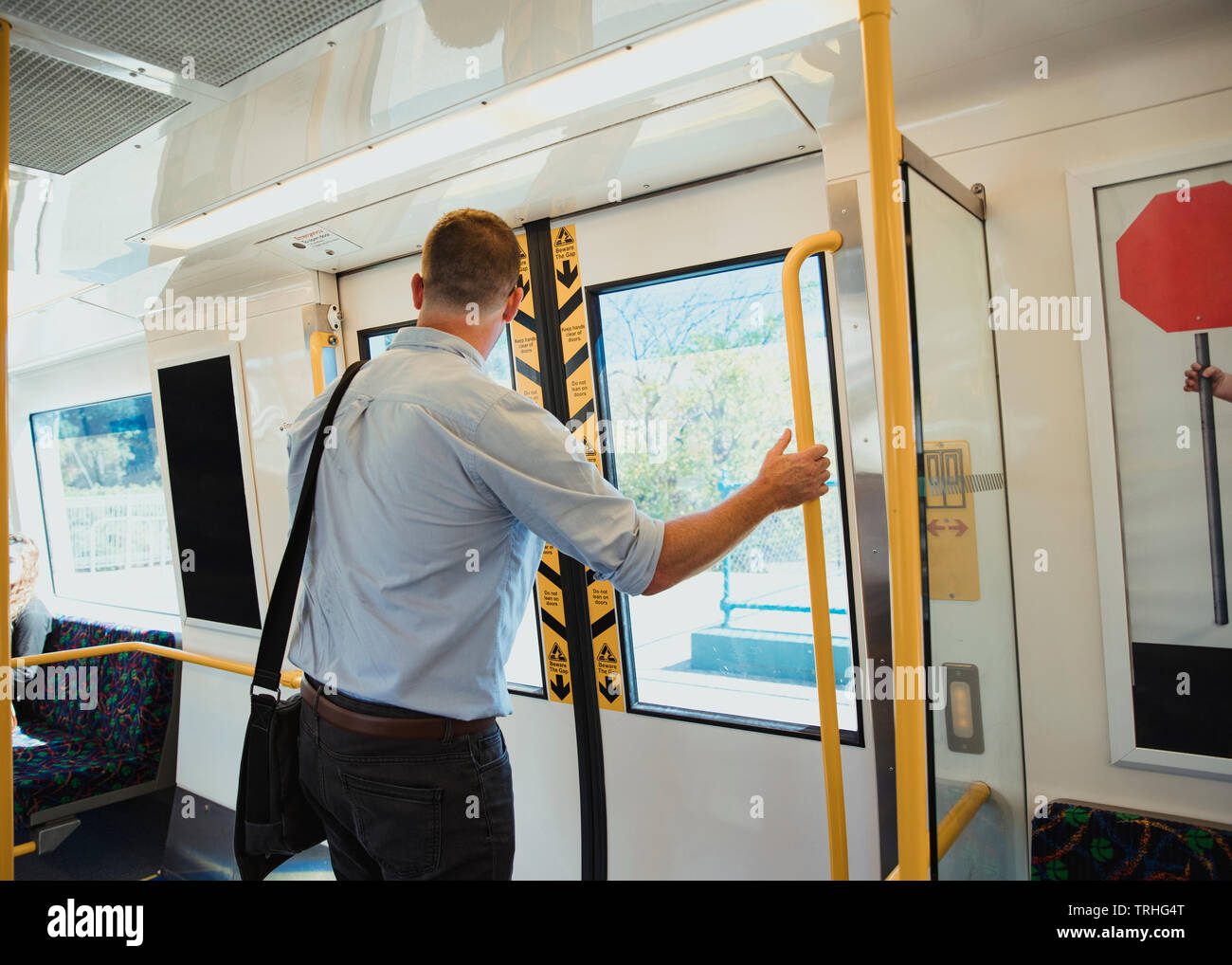 A rear-view shot of a mid-adult businessman standing on a train ...