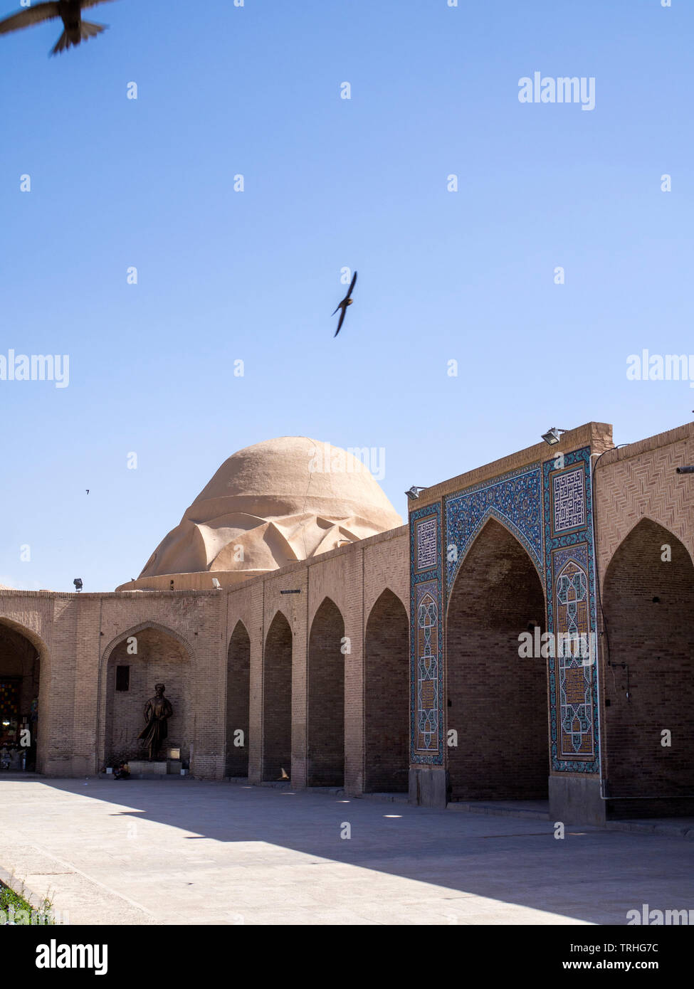 Birds fly over the Kerman Bazaar, known as the Ganjali Khan Complex, in ...