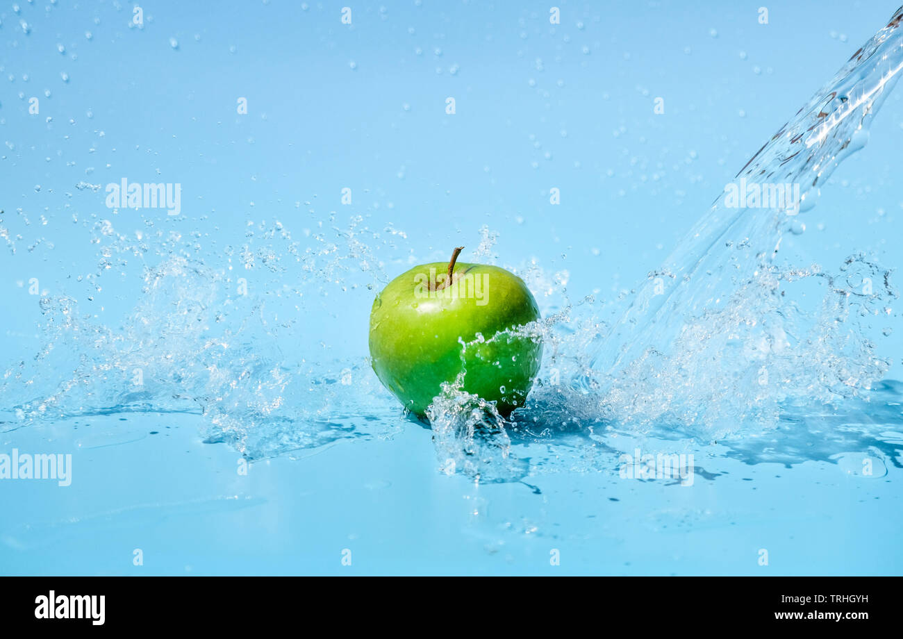 Green apple in water splash on blue background Stock Photo - Alamy