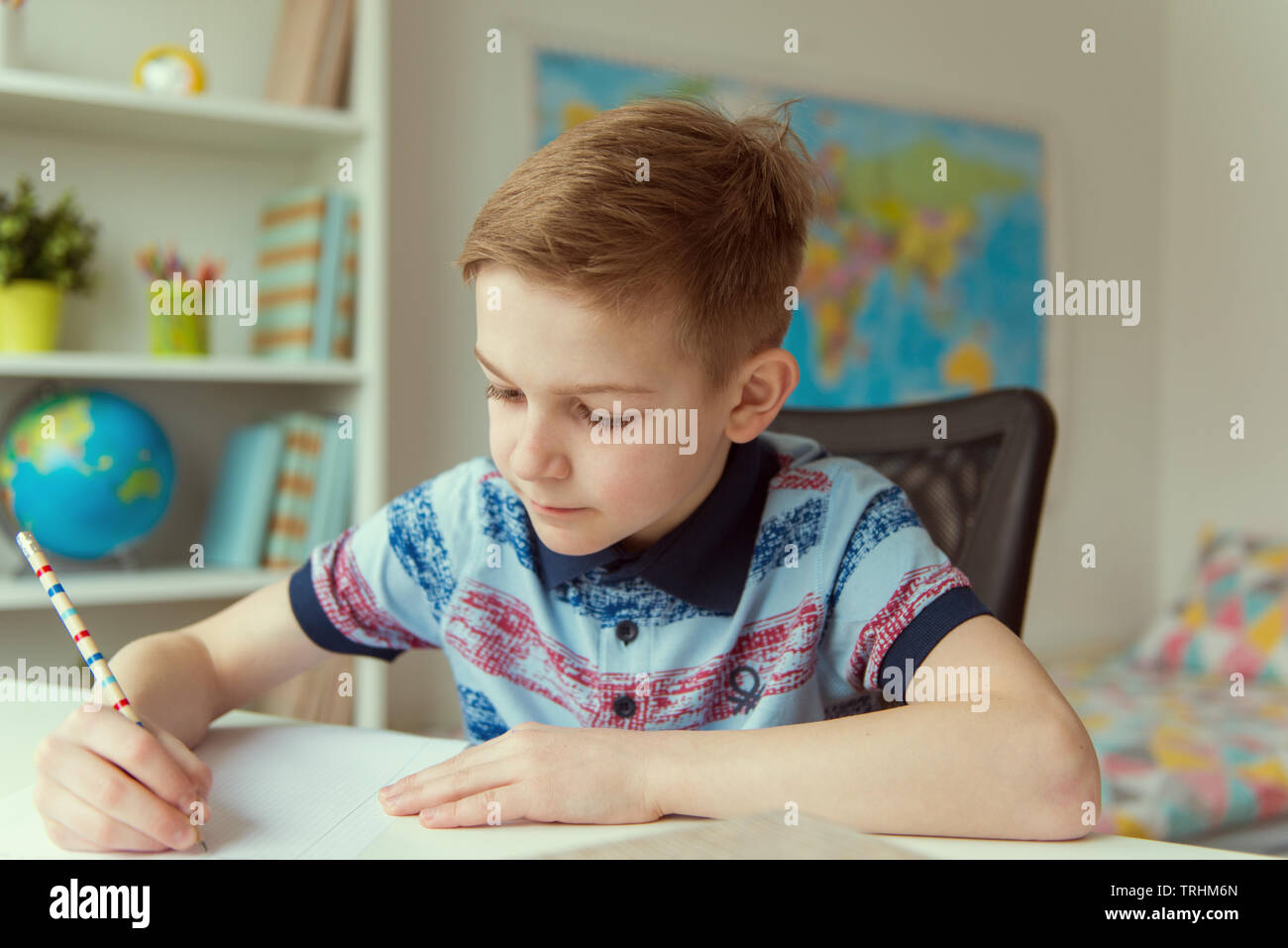 Little smart school boy making homework at desk in his room Stock Photo ...