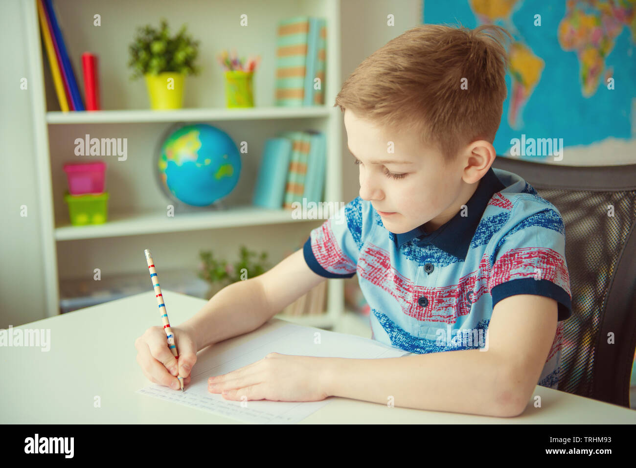 Little smart school boy making homework at desk in his room Stock Photo ...