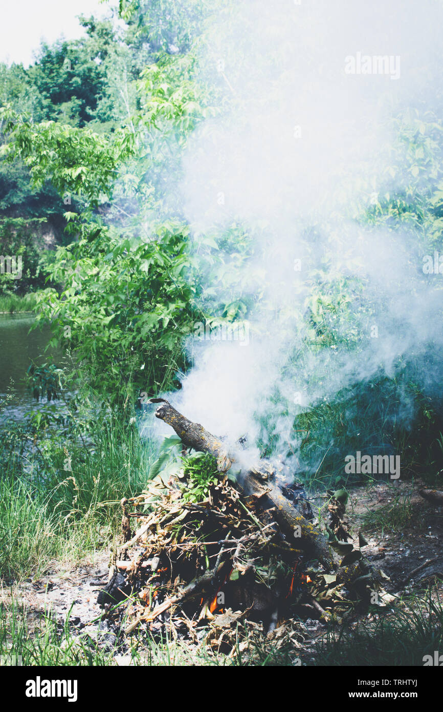 A fire is burned on the ground, and thick smoke rises to the top. Close ...