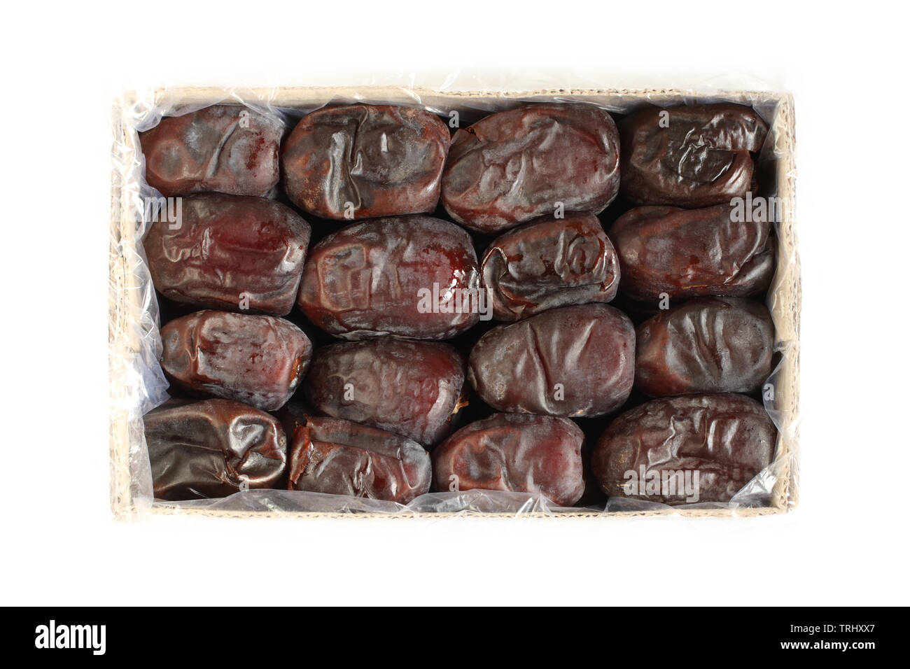 Dried dates arranged in rows in a cardboard box on white background ...