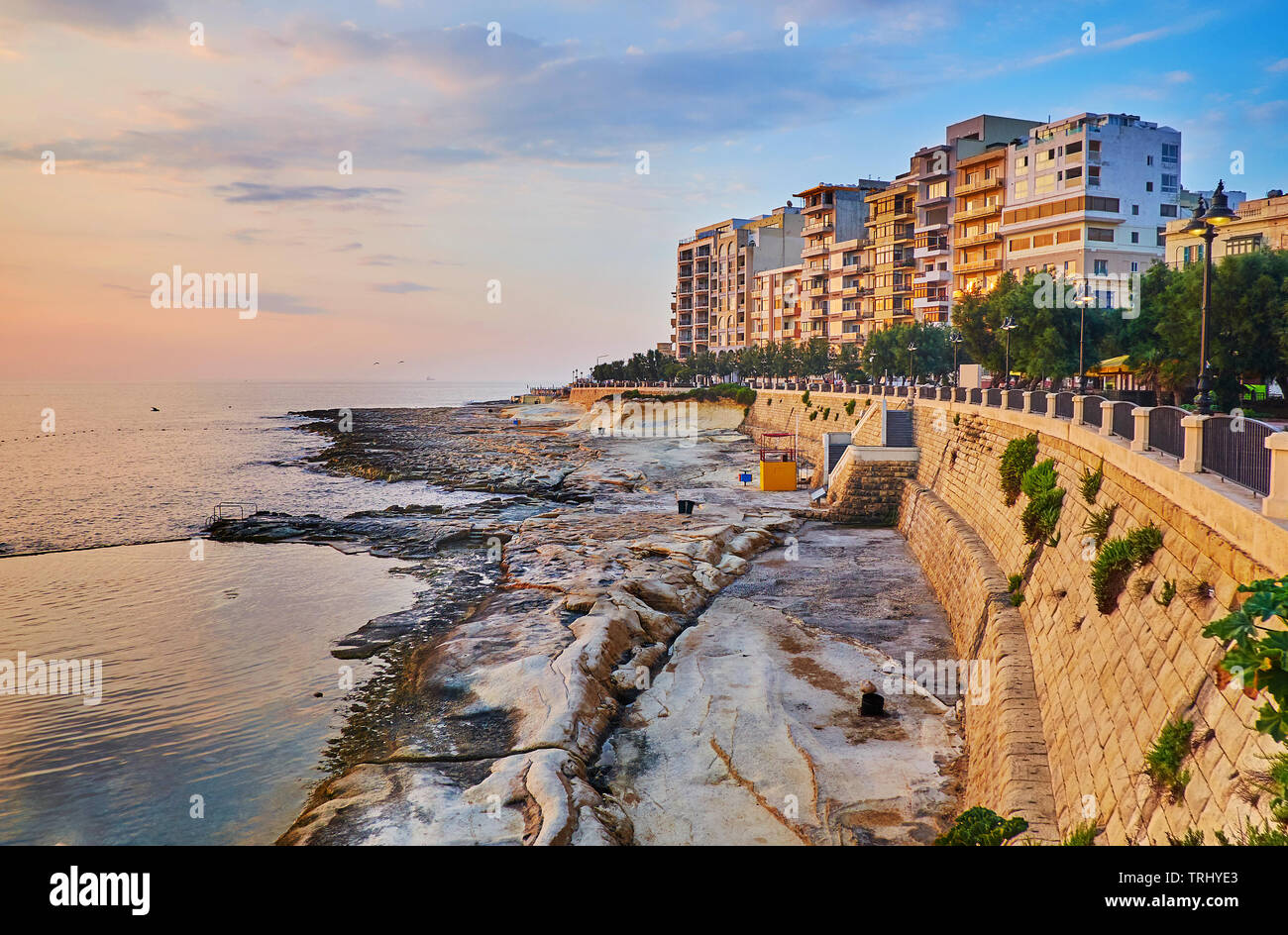 The rocky coast of Sliema with modern residential buildings and lush ...
