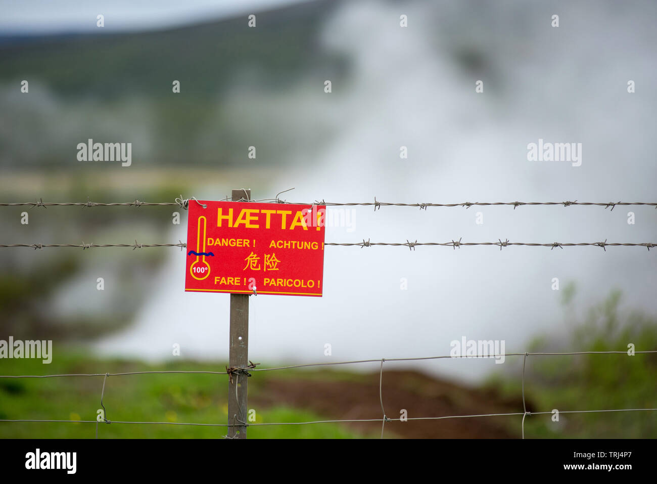 Warning danger sign in different languages near a boiling geothermal ...
