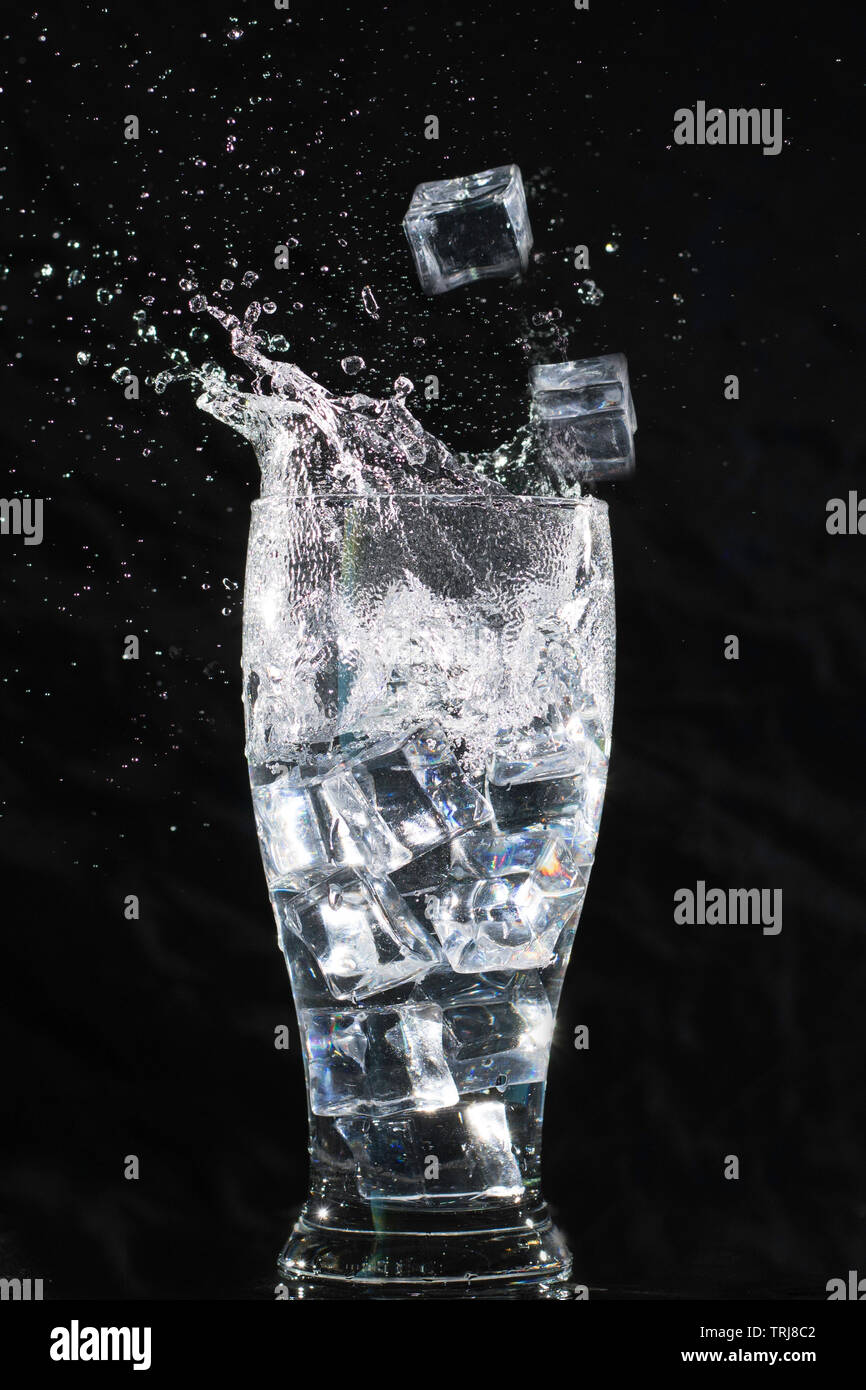 Ice Cubes falling into drinking glass with a splash Stock Photo - Alamy