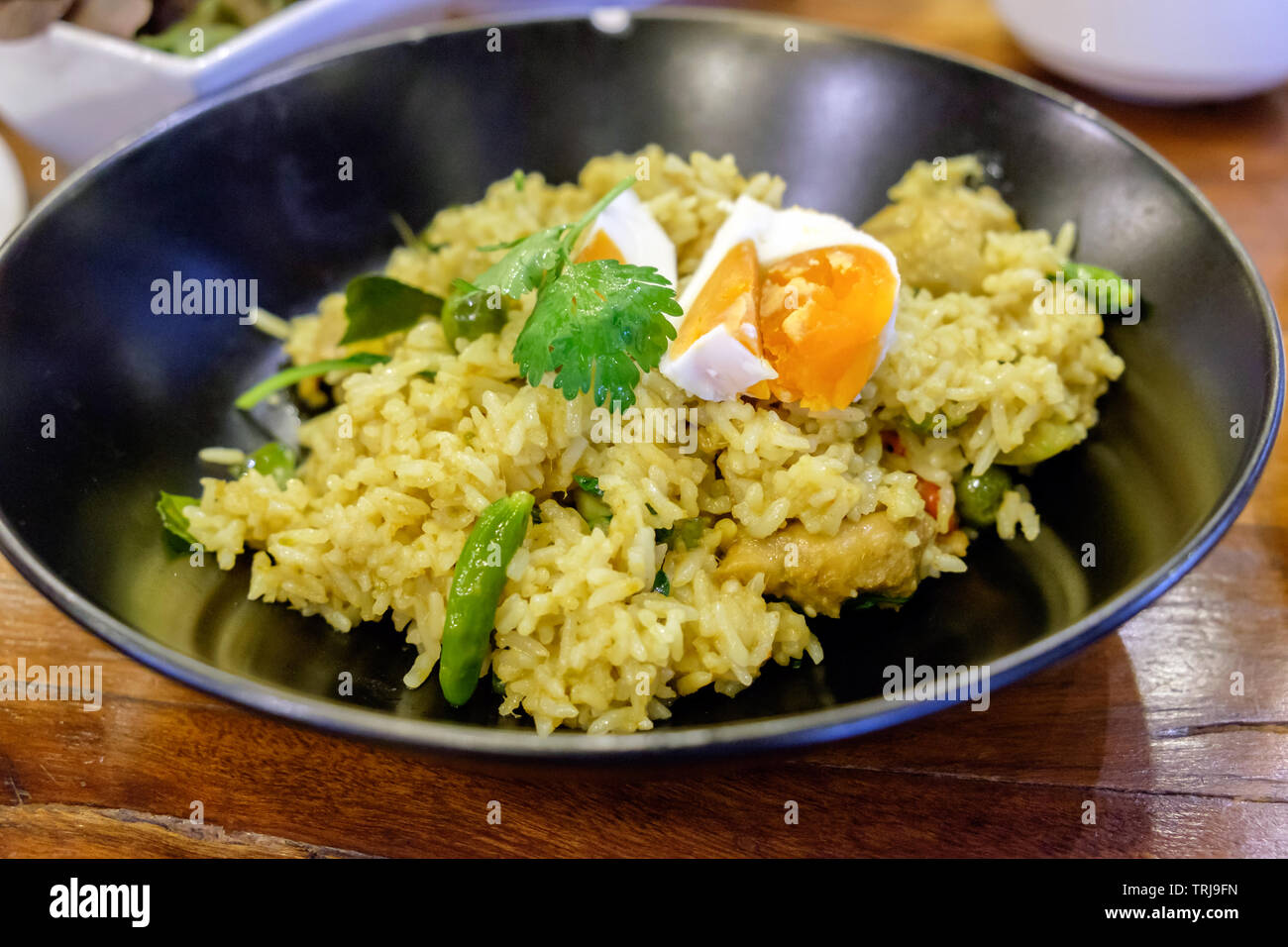 Rice yellow green curry with boiled egg in black dish Stock Photo - Alamy