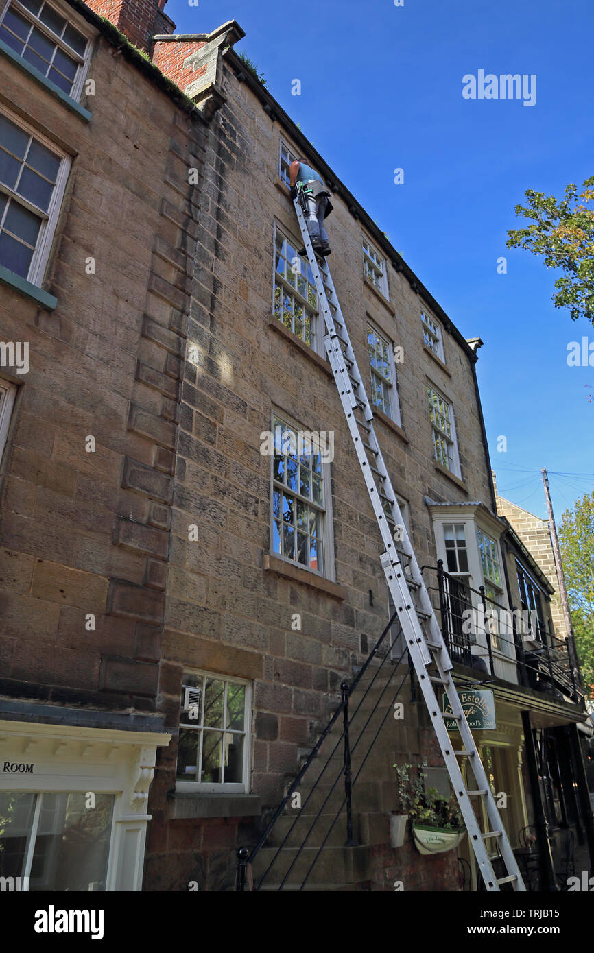 A brave window cleaner scales a very tall ladder on a bright summer's ...