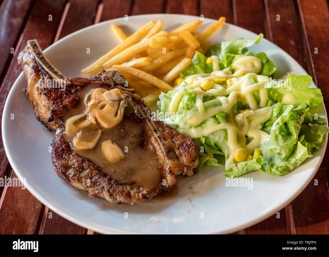 Grilled pork ribs steak well-done with french fries and vegetable on ...