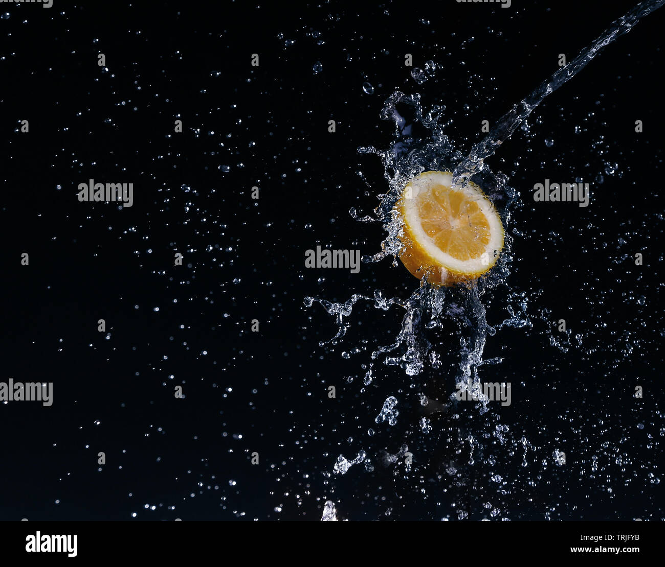 A high-speed shot of a lemon with splashing water, on a black ...