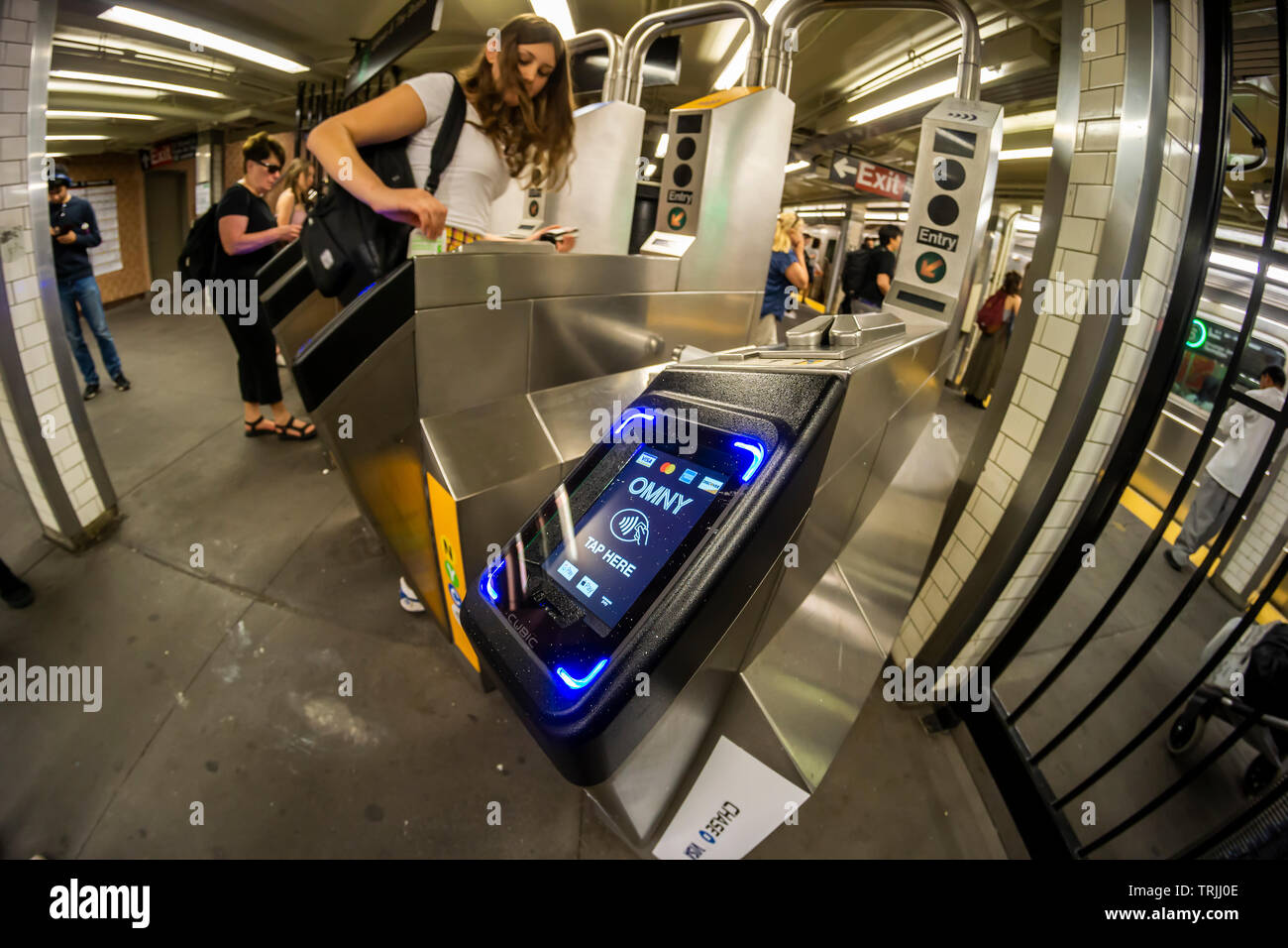 Commuters enter with MetroCards passing OMNY readers mounted on ...
