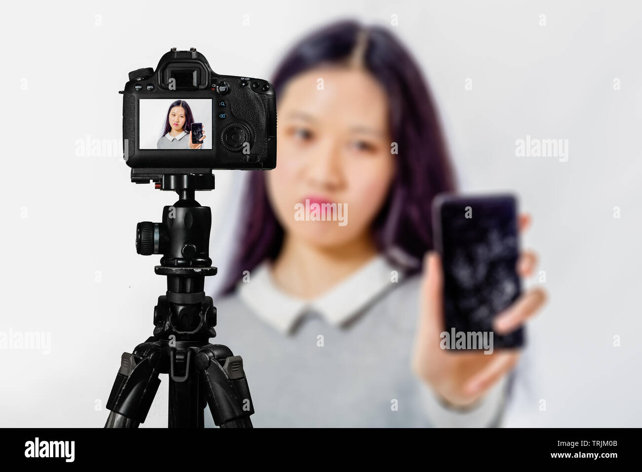 Focus on live view on camera on tripod, teenage girl holds cracked ...