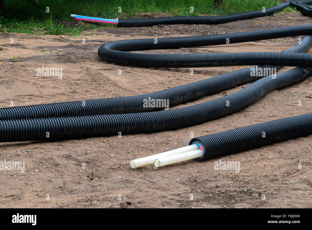 Black PVC electric pipes with wires on the ground. Construction site ...
