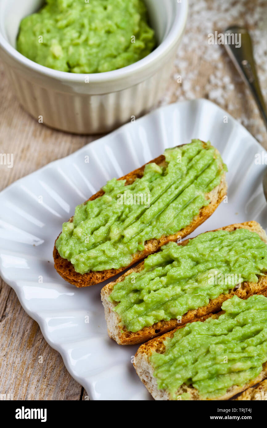 Fresh crostini with avocado guacamole on white plate closeup on rustic ...
