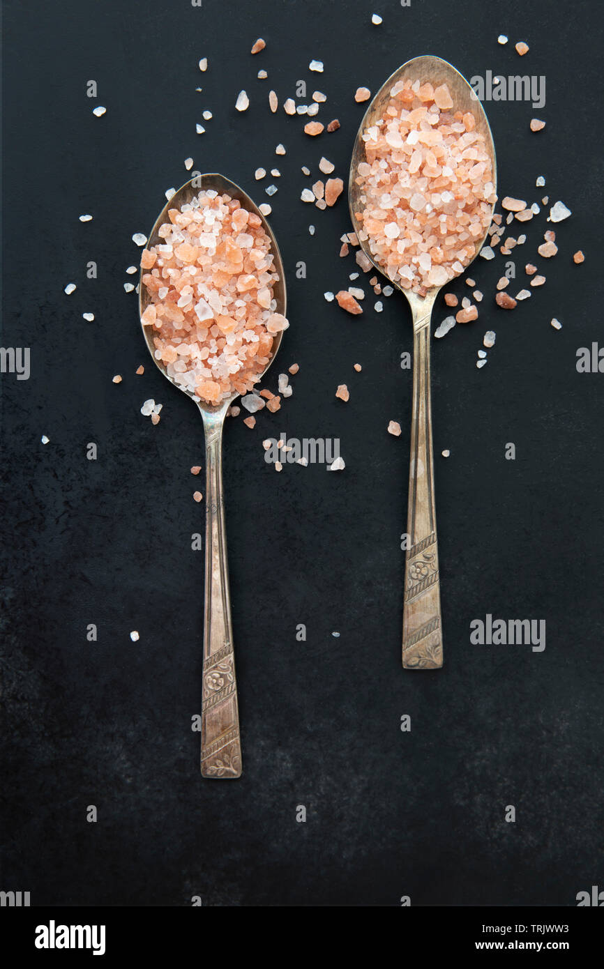 Pink Himalayan salt in old spoons on black background Stock Photo - Alamy
