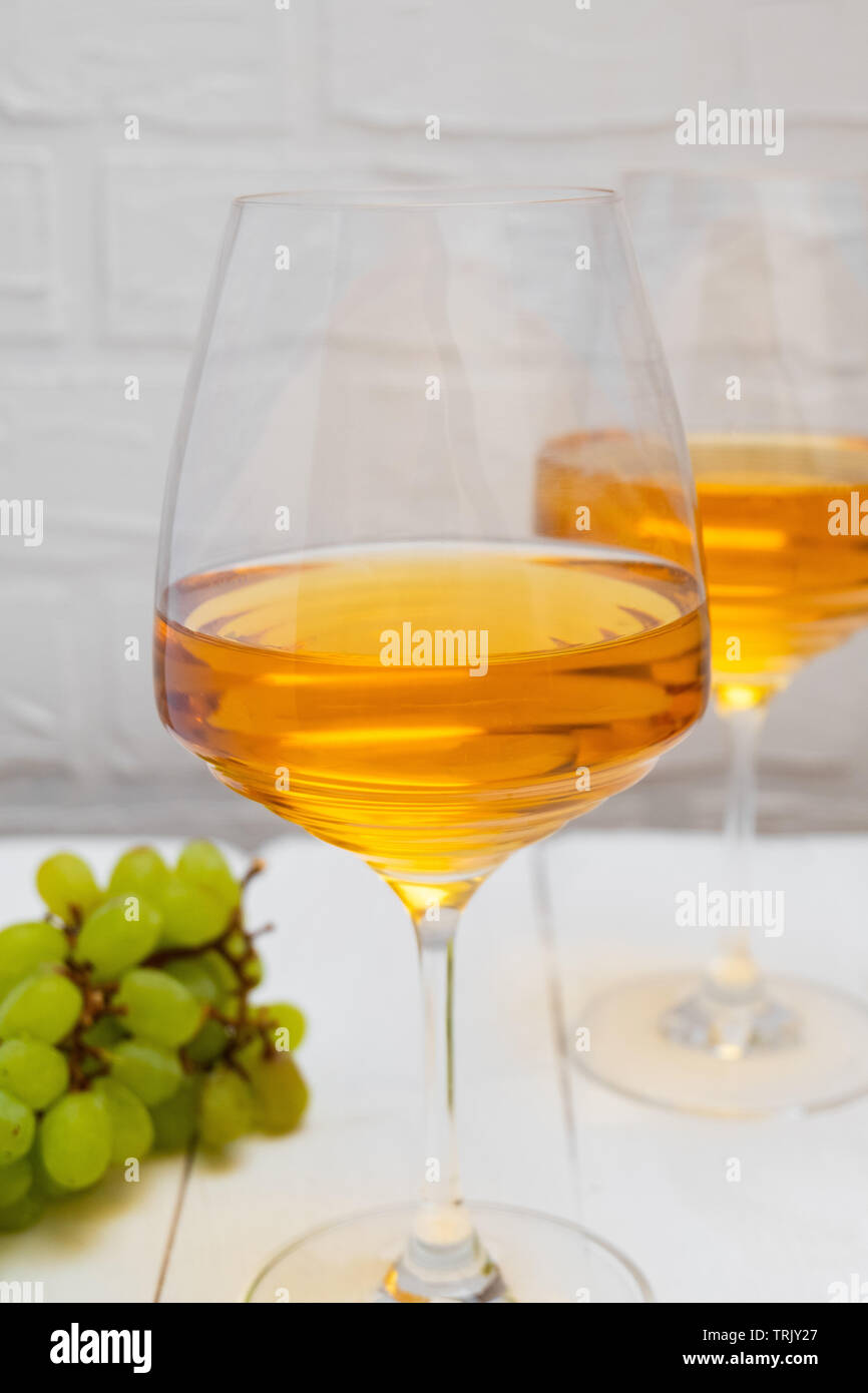 Glasses of Amber wine or scin-fermented white wine with grapes on white ...