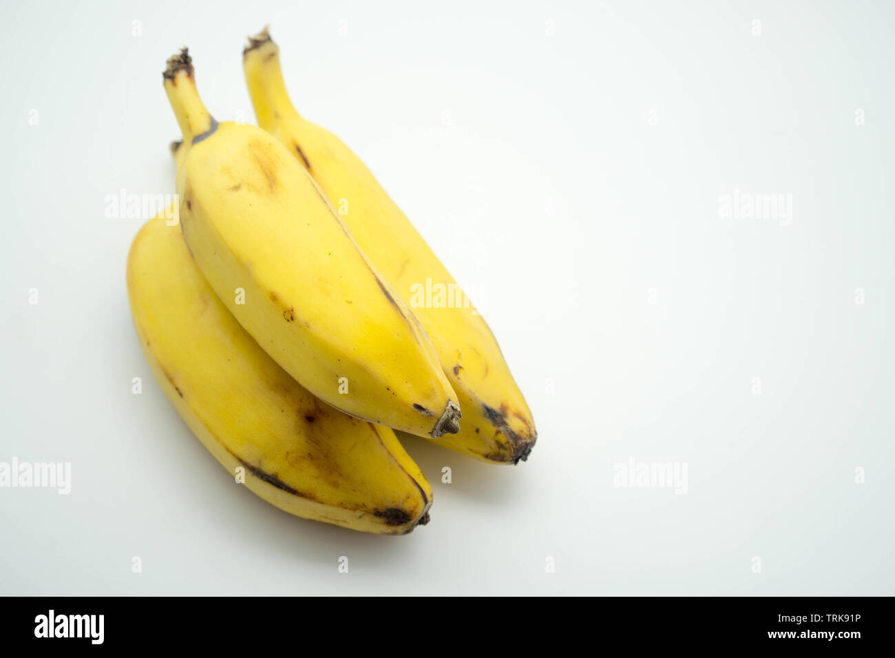 three short ripe bananas stack on each other on an isolated white ...