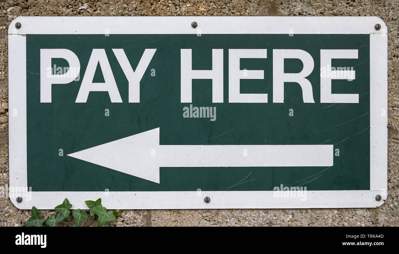 Pay Here sign - white text on dark green background Stock Photo - Alamy