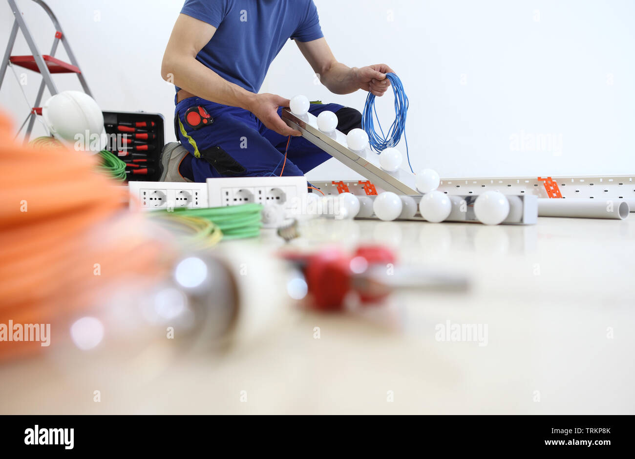 electrician at work installing lamp, with cable in hand, install ...