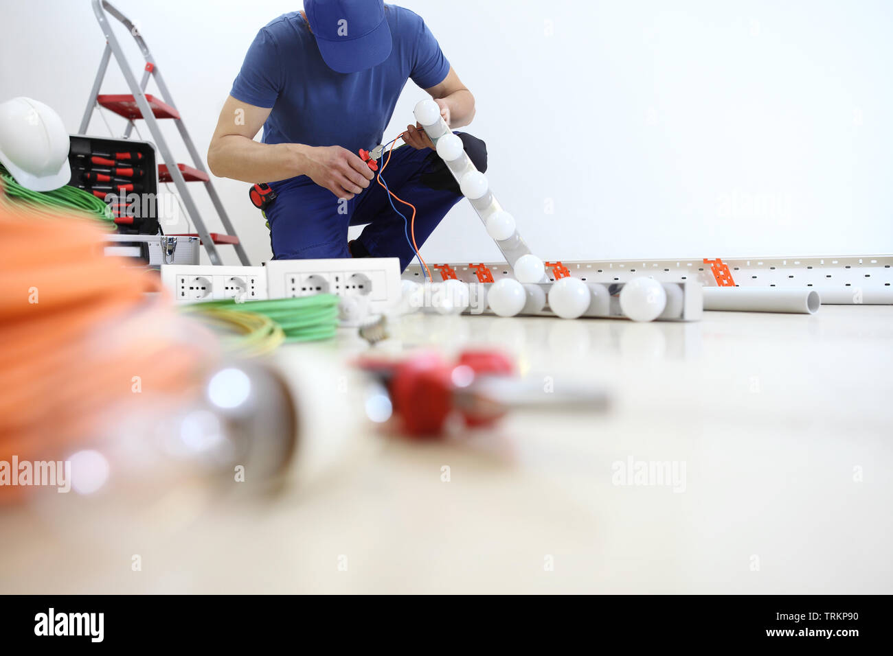 electrician at work installing lamp, cut the cable with nippers ...