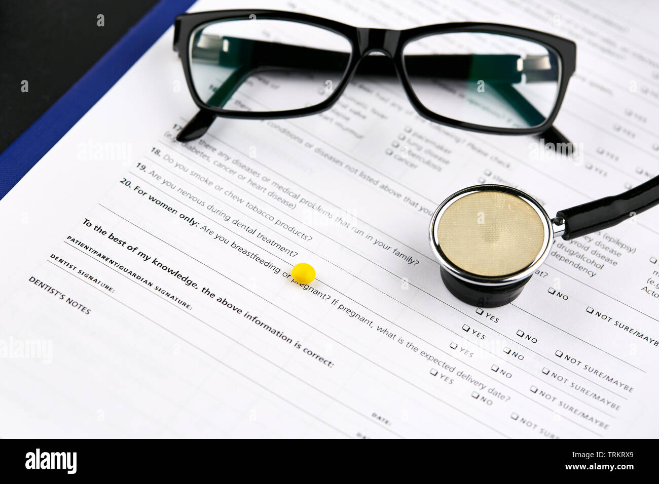Glasses, stethoscope and yellow pill on medical questionnaire form ...