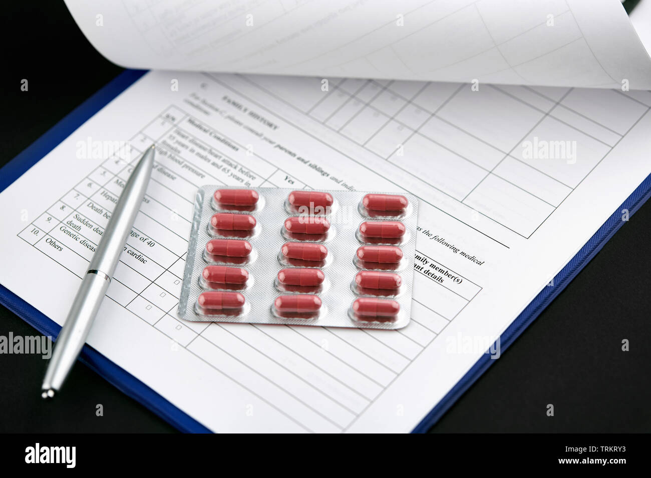 Blister with red pills and silver pen on medical questionnaire form ...