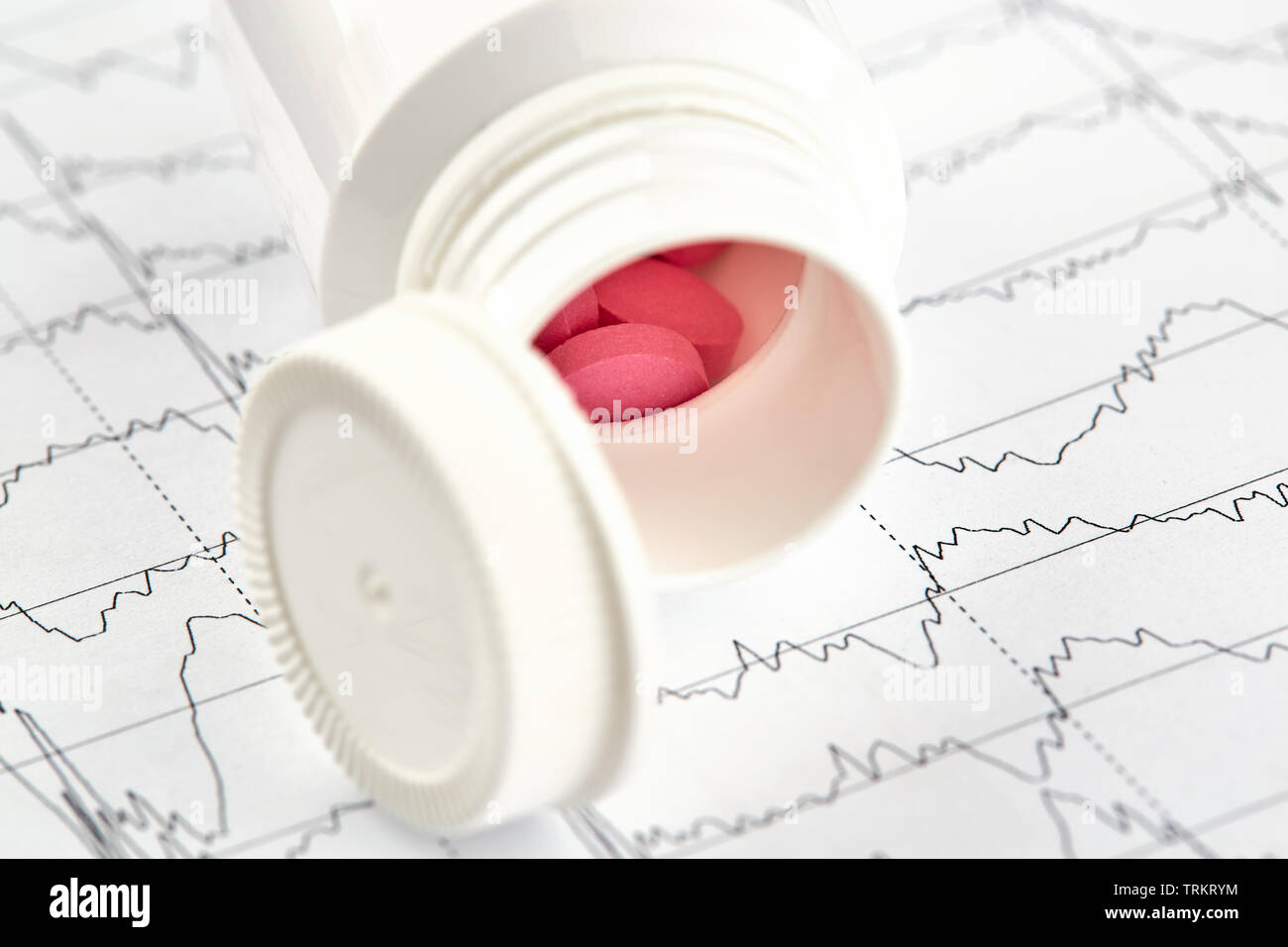 Red pills in white vial and EKG graph on background Stock Photo - Alamy