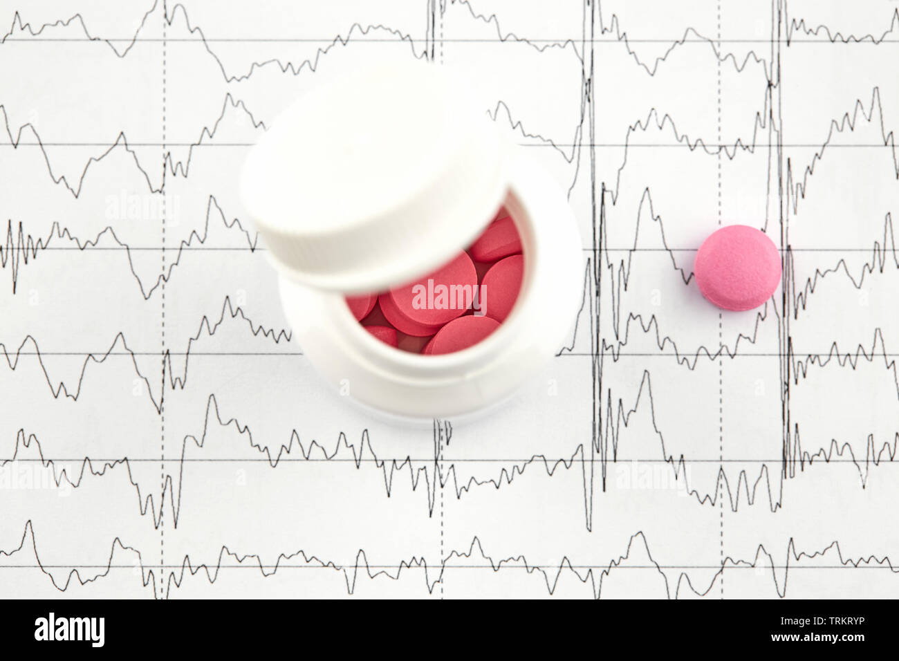 Red pills in white vial and EKG graph on background Stock Photo - Alamy