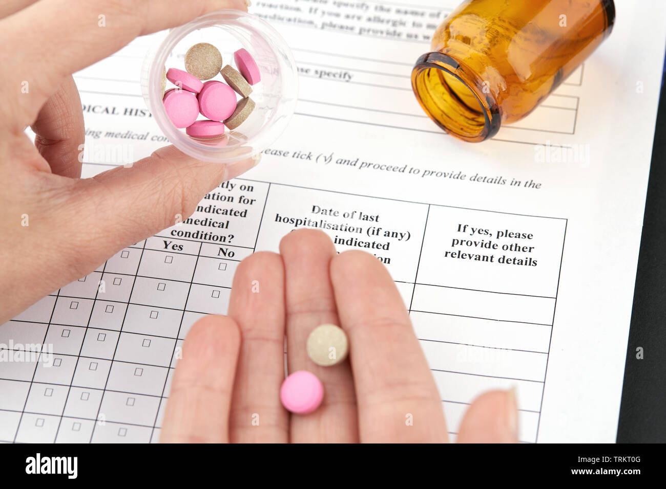 Colorful pills in hand and brown vial with medical questionnaire form ...