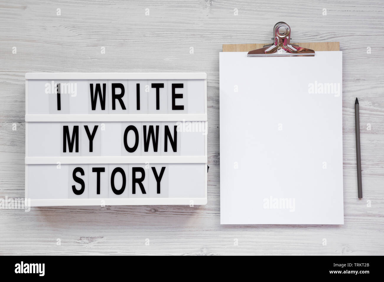 'I write my own story' words on a lightbox, clipboard with blank sheet ...