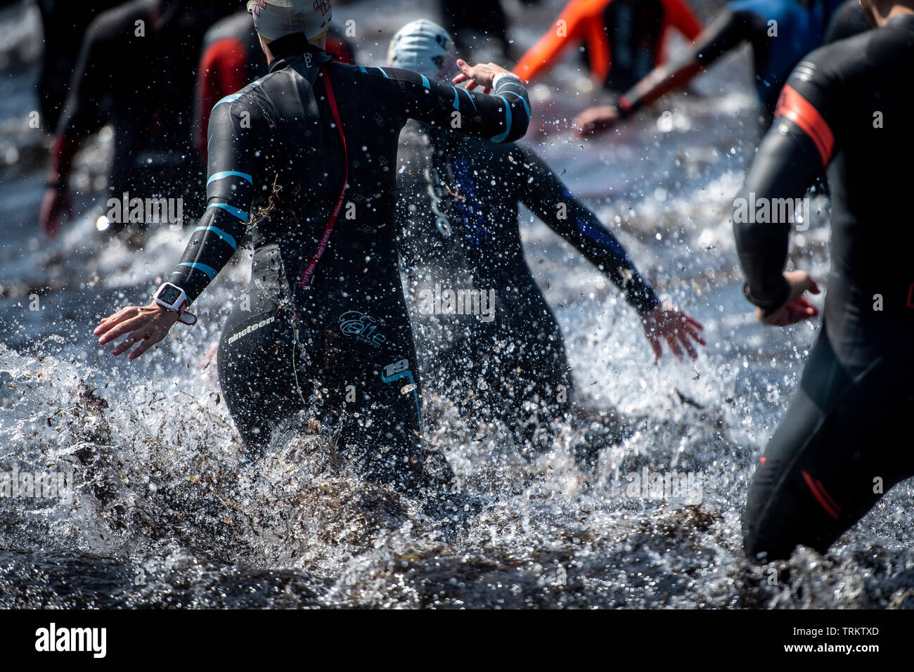 Large groups of triathlon contenders running into the sea during the ...
