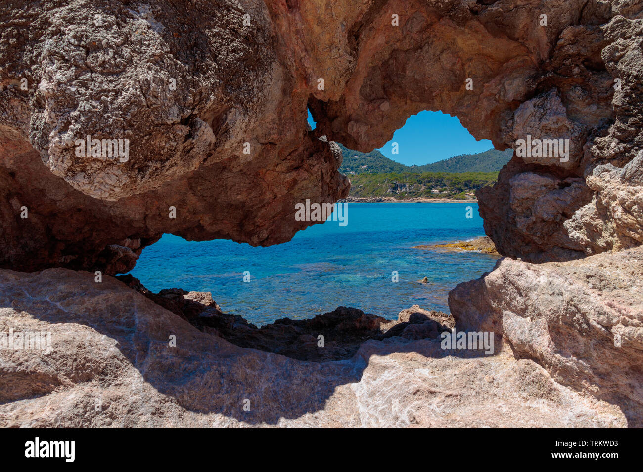 A view through a hole in the rock face revealing the ocean and the ...