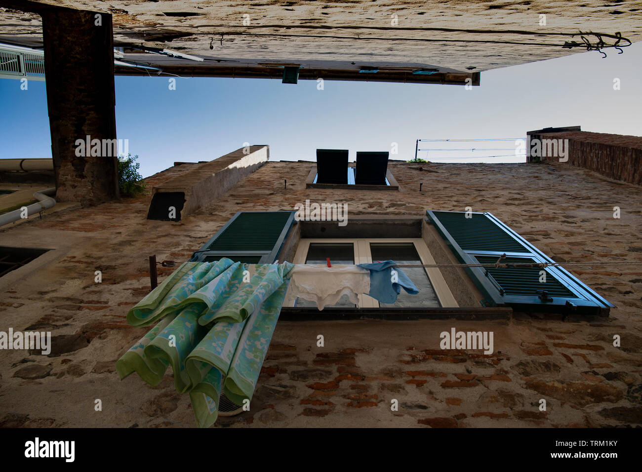 bottom-up view of a narrow alley in Albenga, Italy. Window with clothes ...