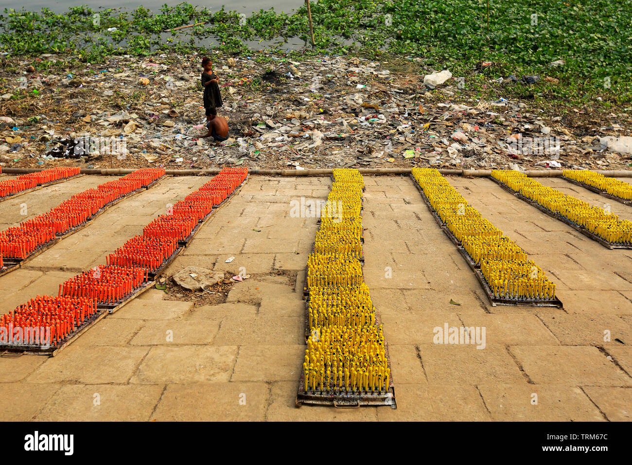 A laborer dries racks of rubber balloon in the sun as he works at a ...