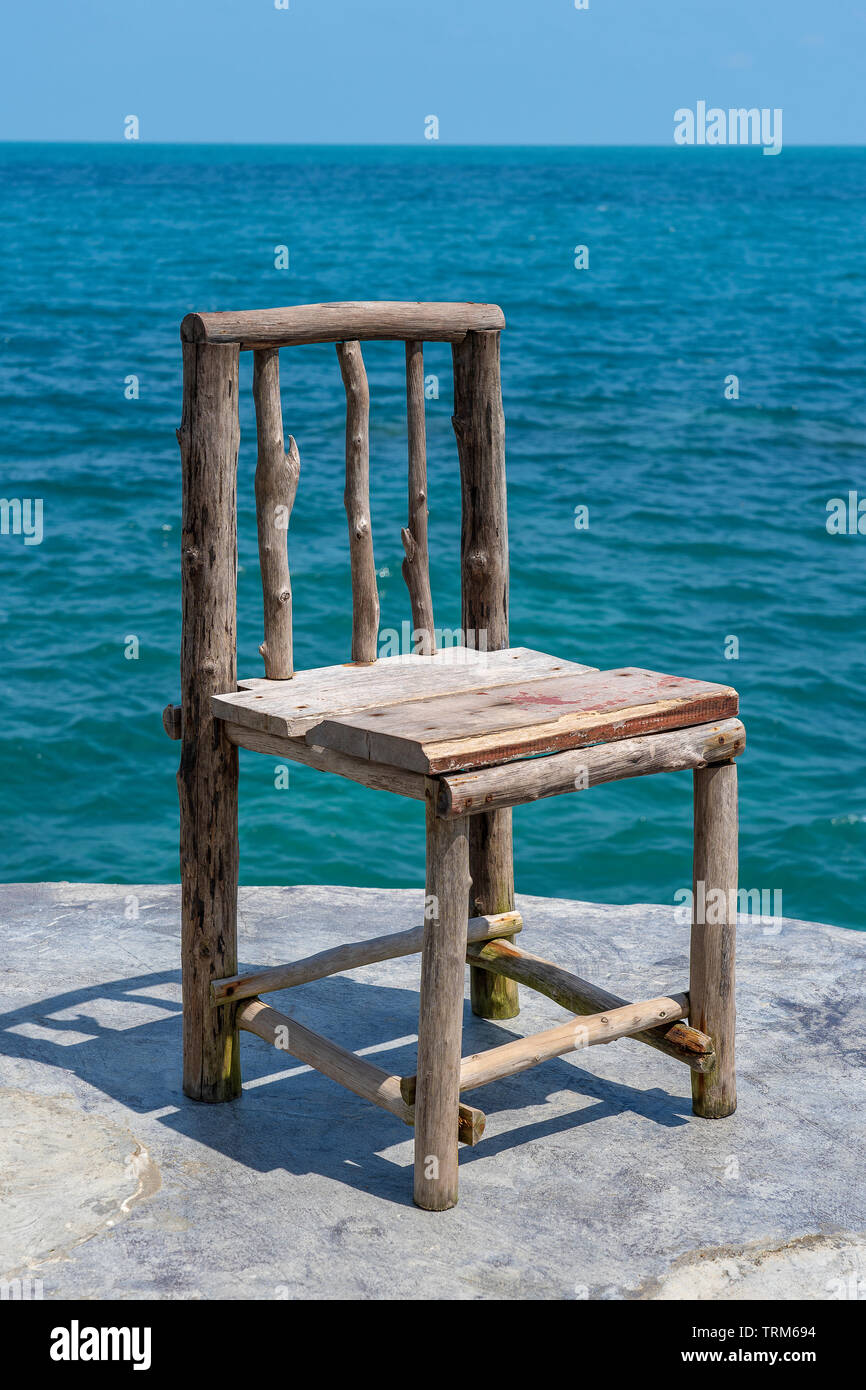 Wooden chair in empty cafe next to sea water in tropical beach. Close up. Island Koh Phangan ...