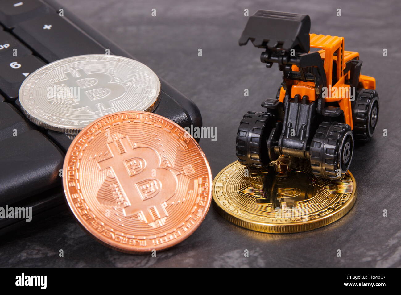 Bitcoin coins, computer keyboard and miniature excavator as symbol of ...