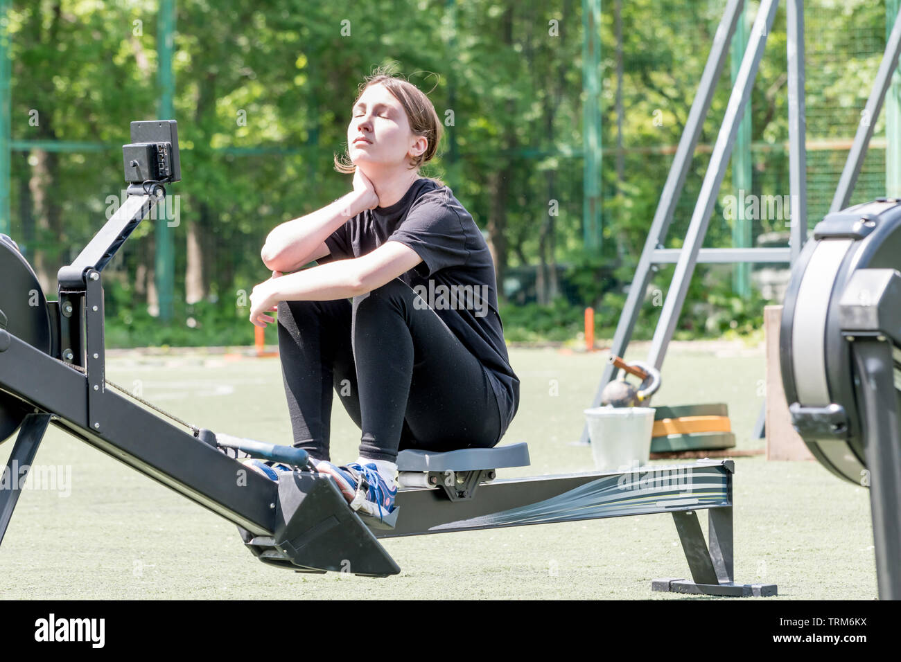 Young caucasian girl sits on rowing machine and ready for workout ...