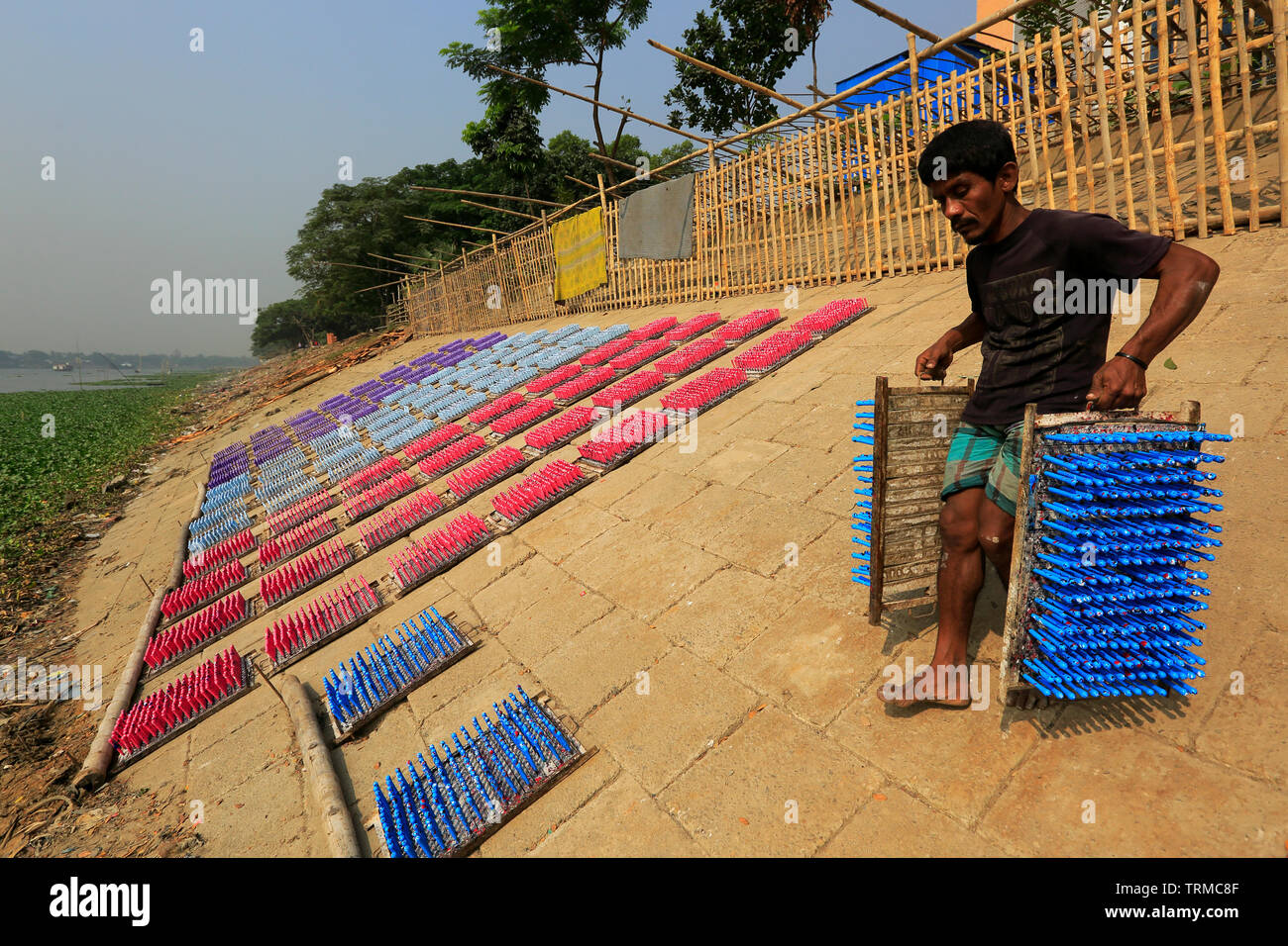 A laborer dries racks of rubber balloon in the sun as he works at a ...