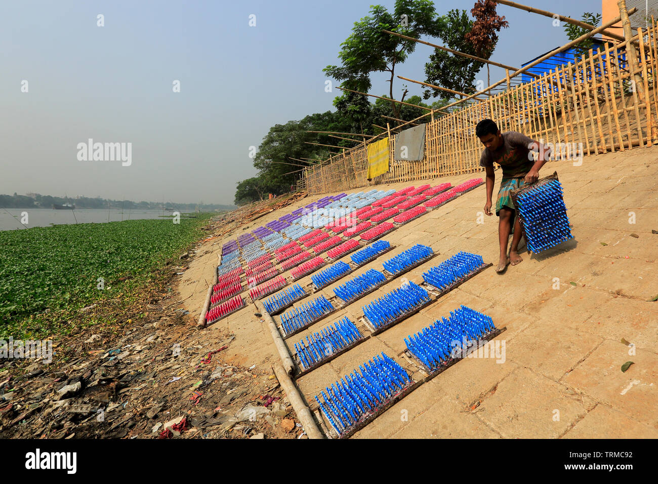 A laborer dries racks of rubber balloon in the sun as he works at a ...