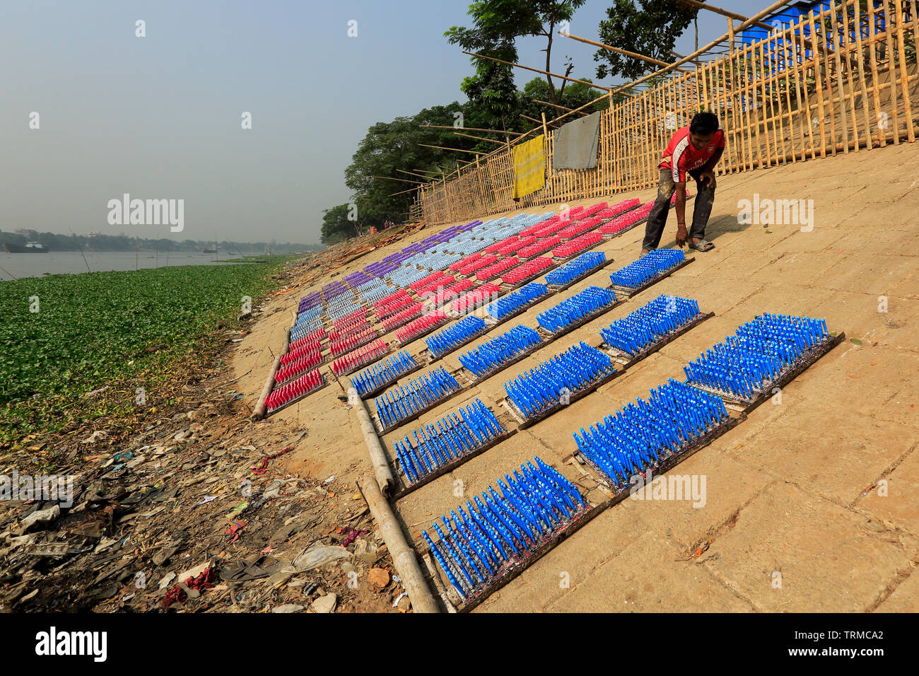 A laborer dries racks of rubber balloon in the sun as he works at a ...