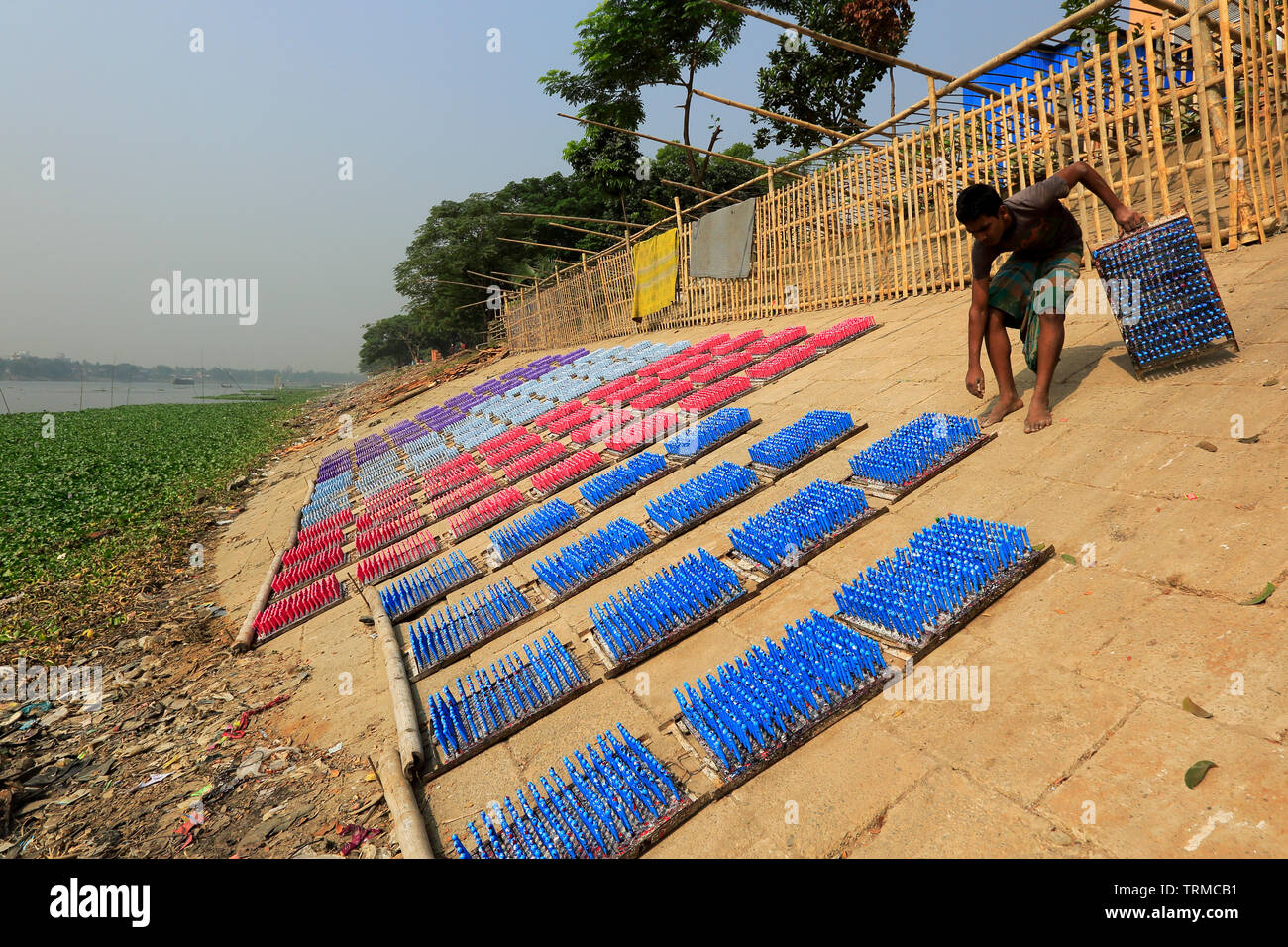 A laborer dries racks of rubber balloon in the sun as he works at a ...