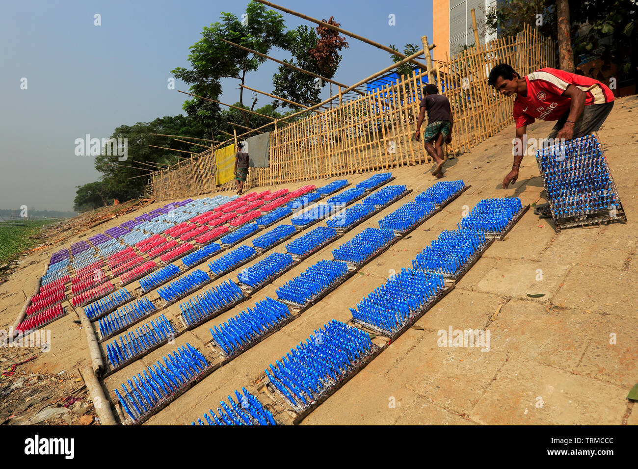 A laborer dries racks of rubber balloon in the sun as he works at a ...