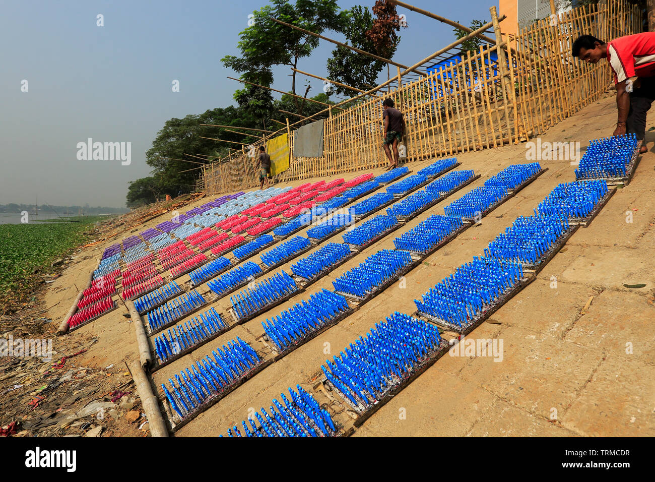A laborer dries racks of rubber balloon in the sun as he works at a ...