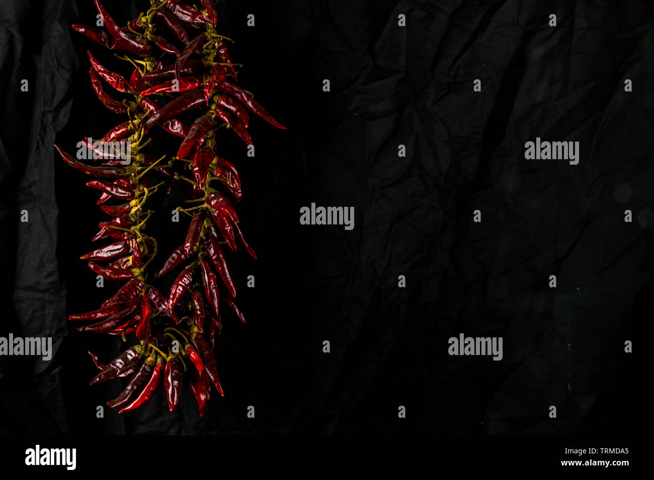 Hungarian paprika pepper string, black background, copy space on right ...