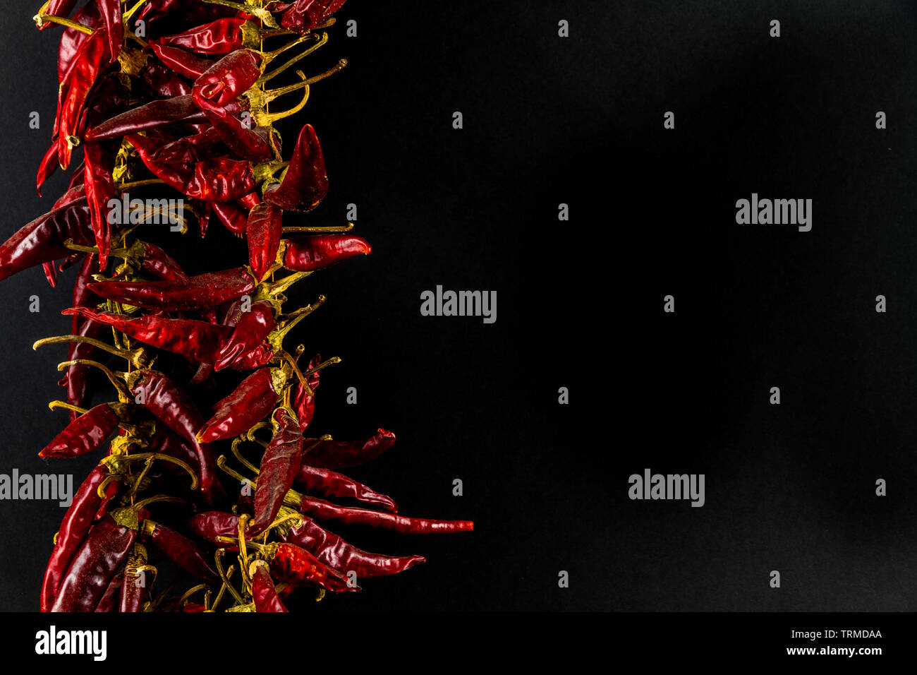Hungarian paprika pepper string, black background, copy space on right ...