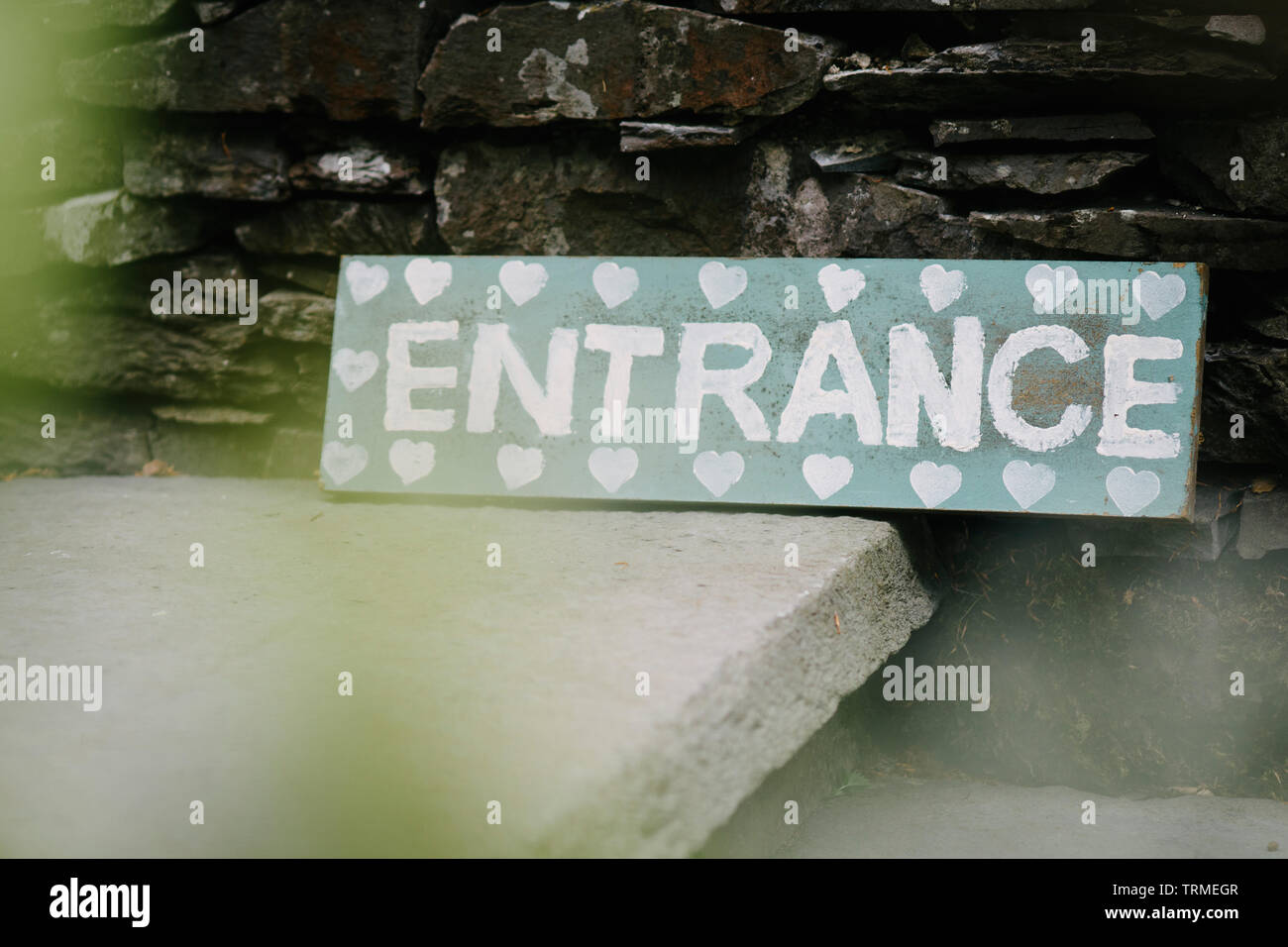 rustic wooden entrance sign against stone wall Stock Photo - Alamy